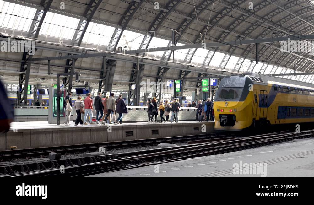 People walk by train at platform at Amsterdam Central Station, static ...