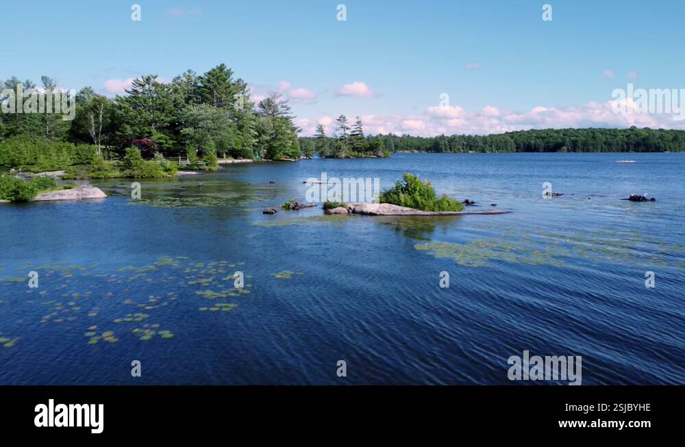 Forward and low over tiny rock island on Big Bald Lake in cottage ...