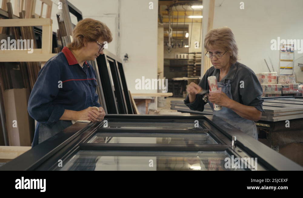 Female artisans are cleaning the wooden window at the carpentry ...