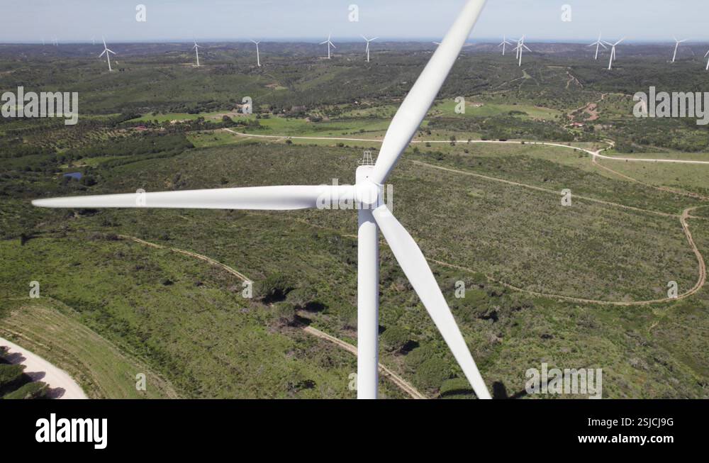 Aerial - wind turbine blades turning on onshore wind farm. Descending ...
