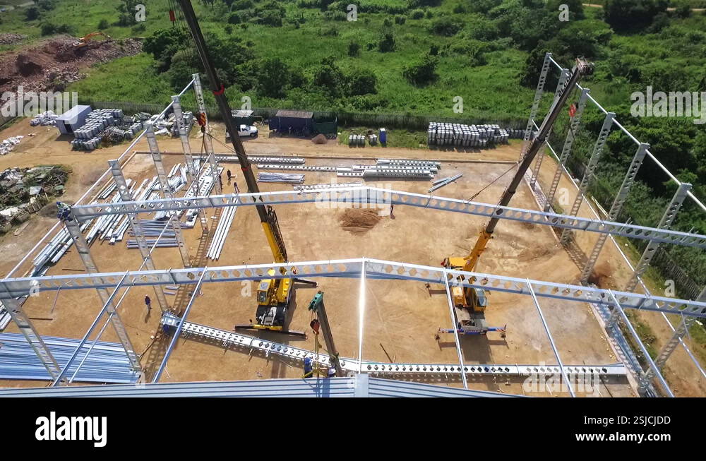 Drone Overhead, Construction Cranes Lift Steel Beam as Workers Attach to Stock Video Footage - Alamy