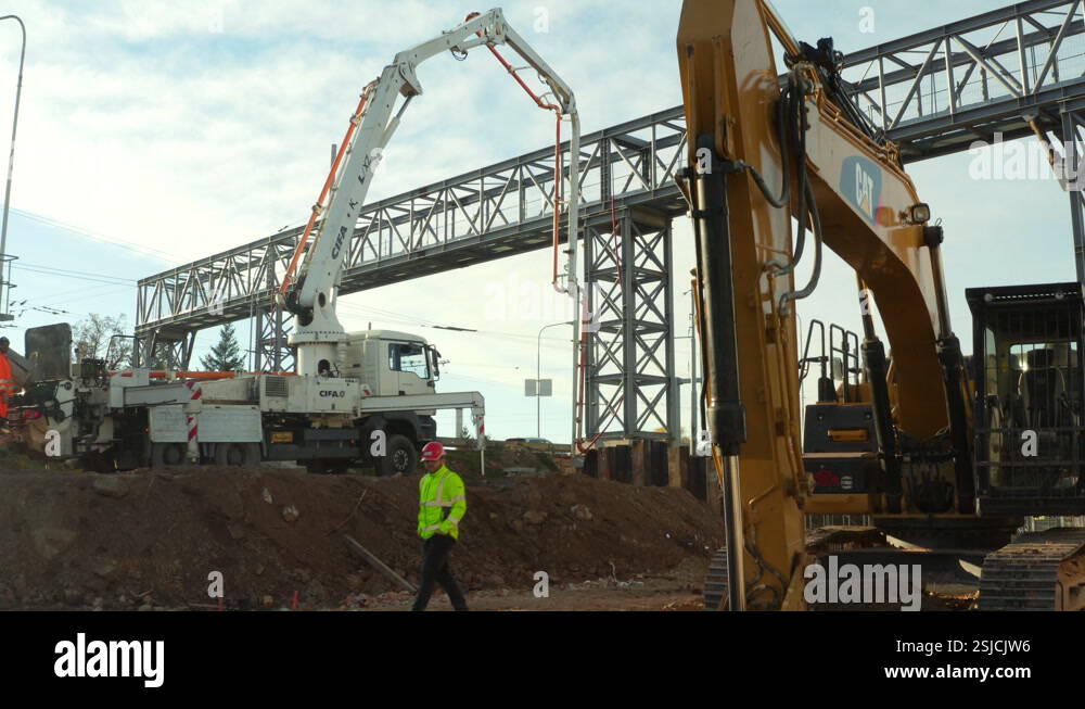 Construction foreman walking leisurely between heavy duty vehicles ...