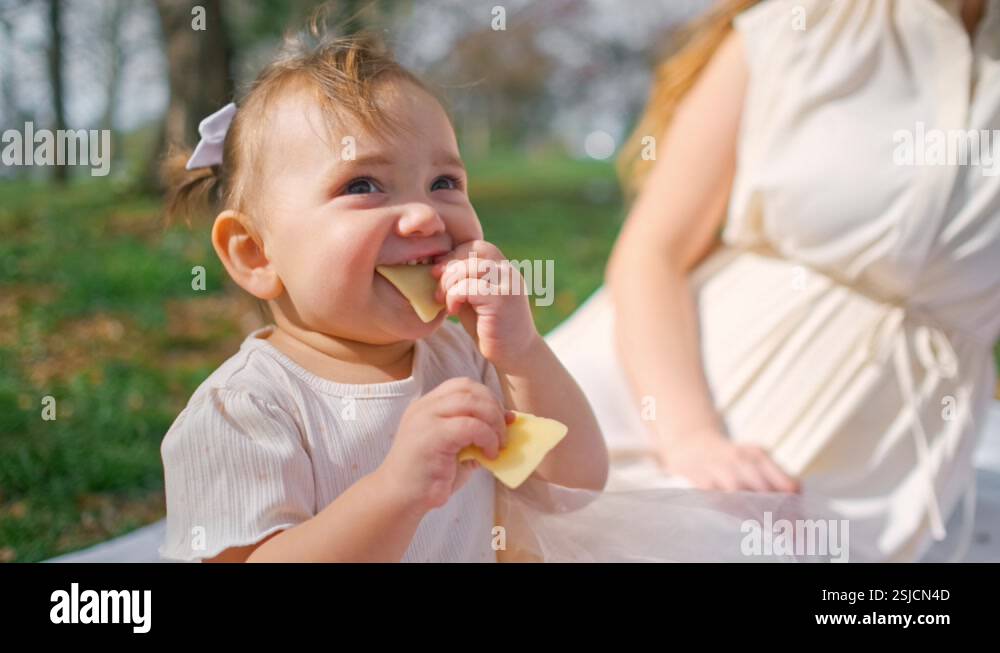 Little girl laughing and eating cheese during a picnic in a park in ...
