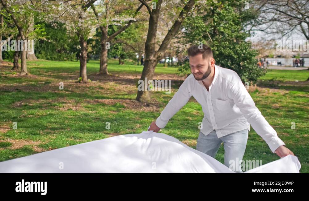 Married couple are stretching out a blanket preparing to have a family ...