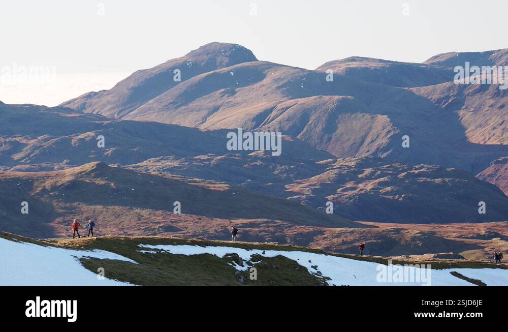 Hikers approaching the summit of Helvellyn, Lake District, UK, with ...