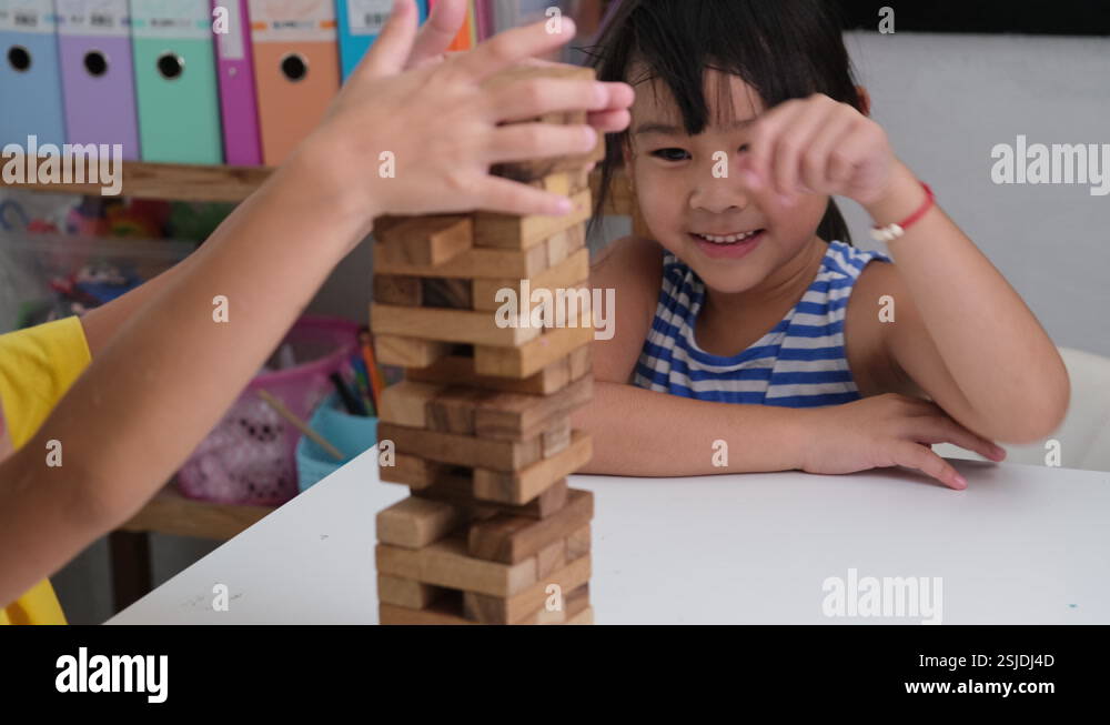 Two children playing Jenga board game on table in room at home Stock ...