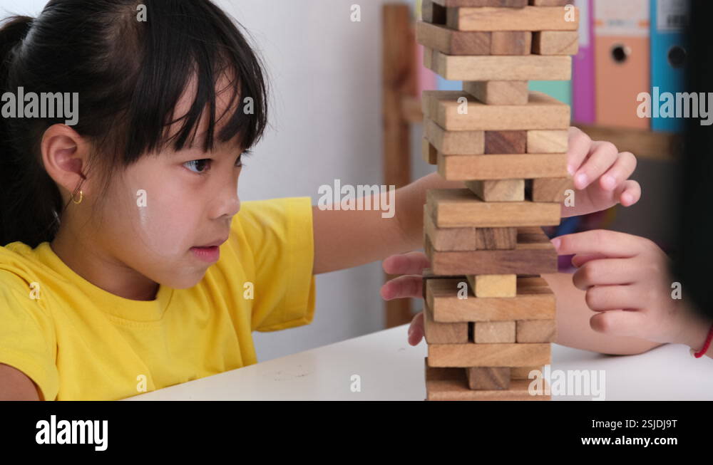 Two children playing Jenga board game on table in room at home Stock ...