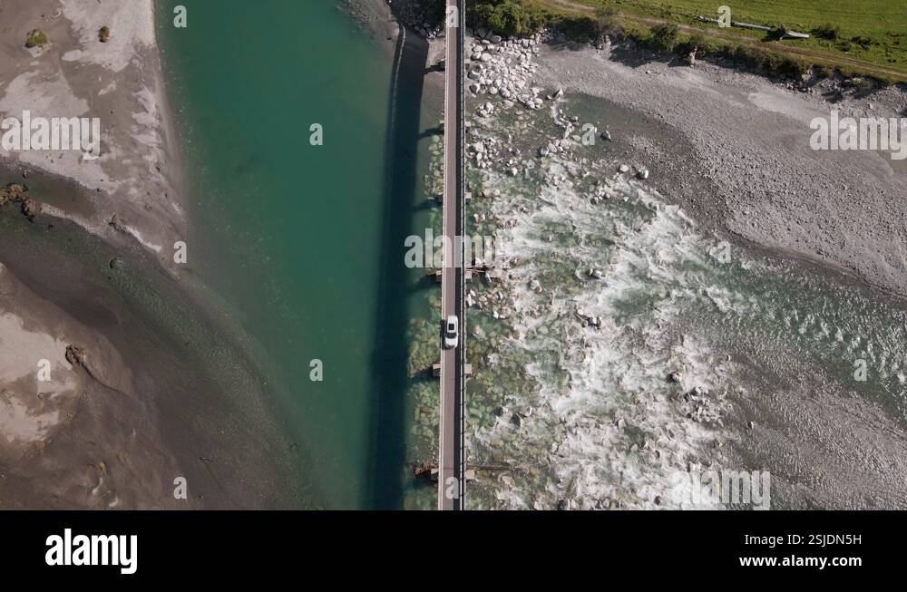 Car crossing one lane bridge over wide, shallow river; aerial top view ...