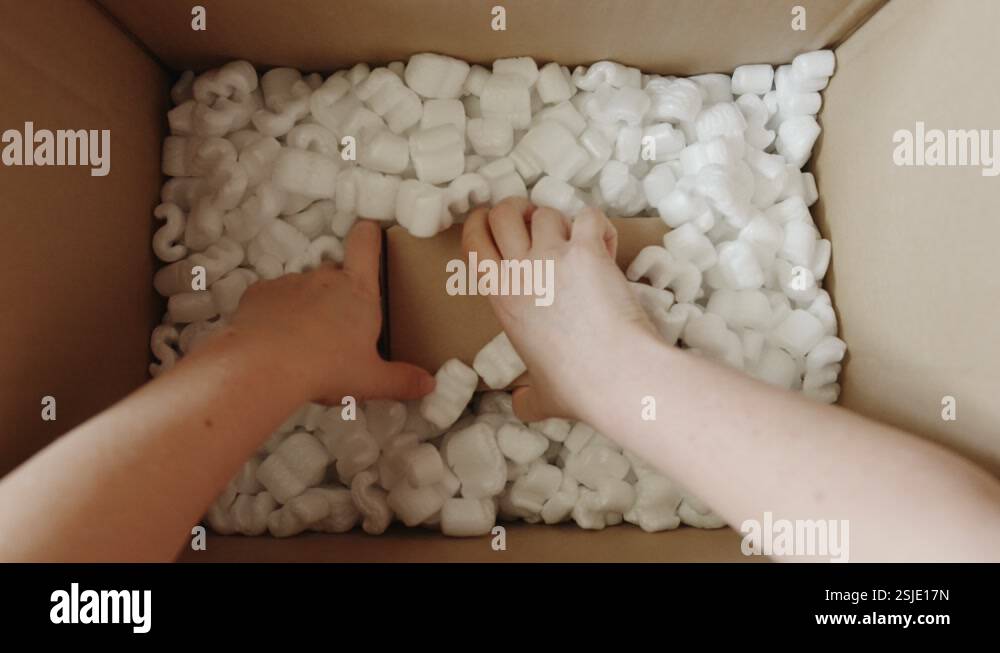 Female hands take out a parcel package from cardboard box with packing ...