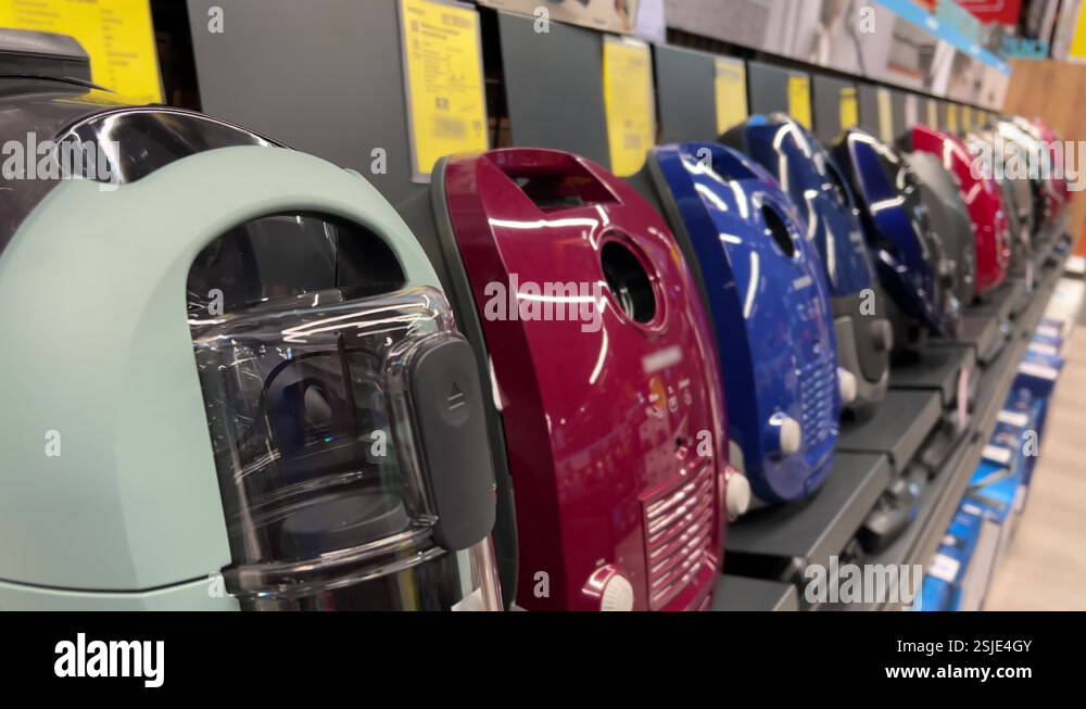 Rows of new vacuum cleaners line the shelves of a home appliance store ...