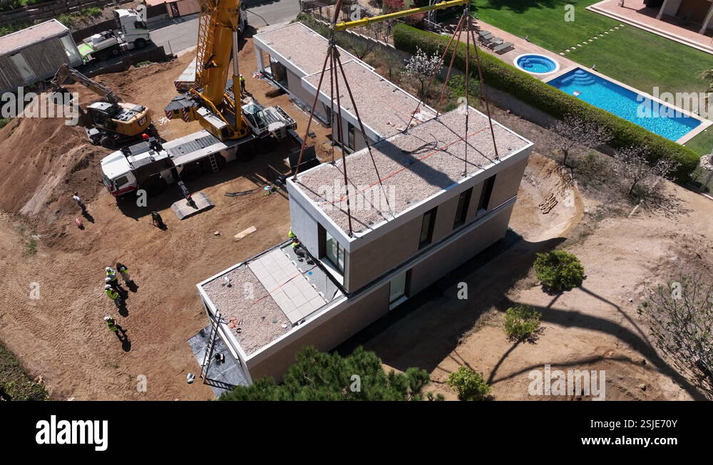 Modular housing suspended by crane installed onto foundation plot ...