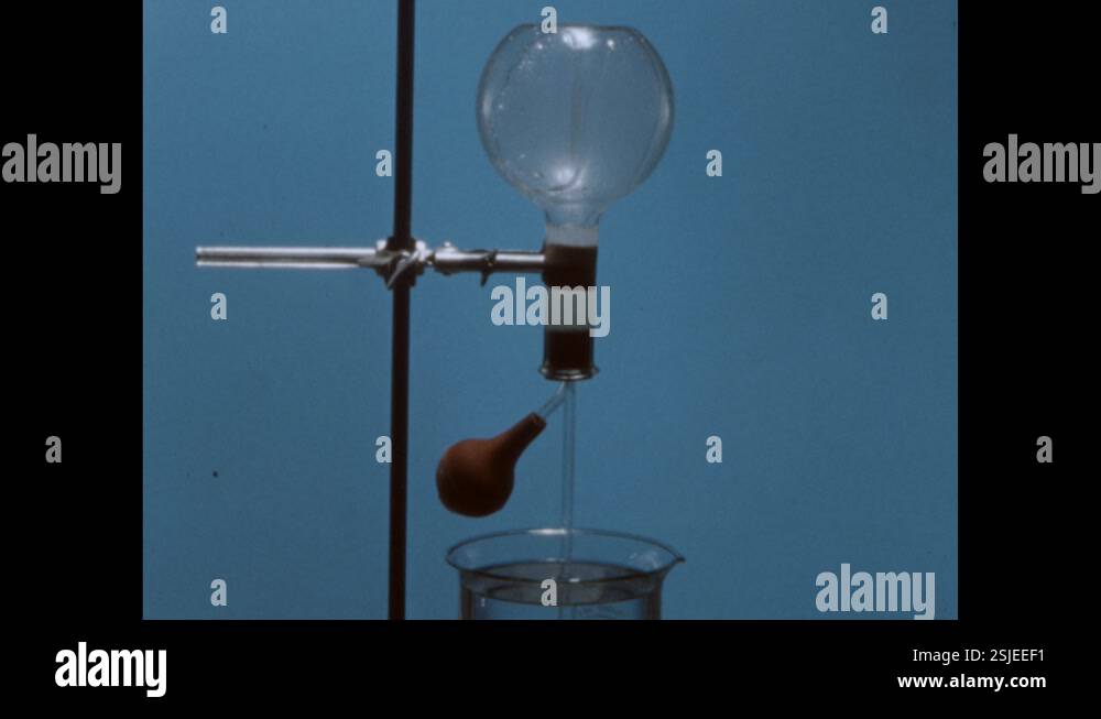 1950s: Scientist squeezes rubber hand syringe of contraption. Water ...