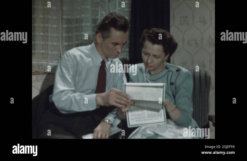 1950s: Living room, man, woman sit, review paperwork, man takes paper ...