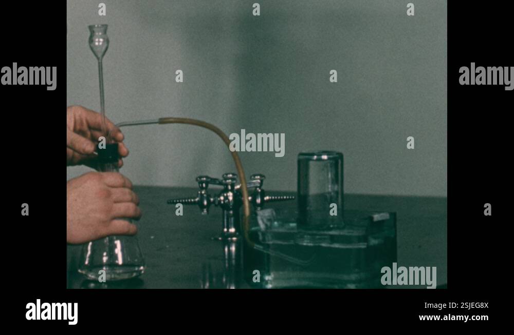 1950s: Hand adjusts beakers and tubes in a laboratory setup. Hand ...