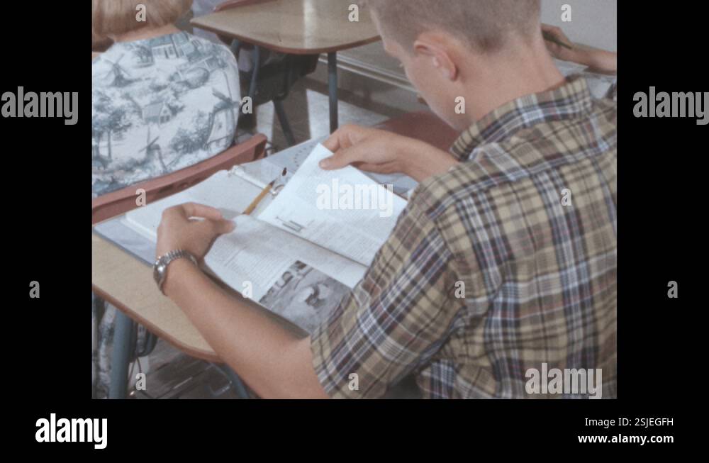 1940s: Boy looks through textbook. Clapperboard. Boy traces writing ...