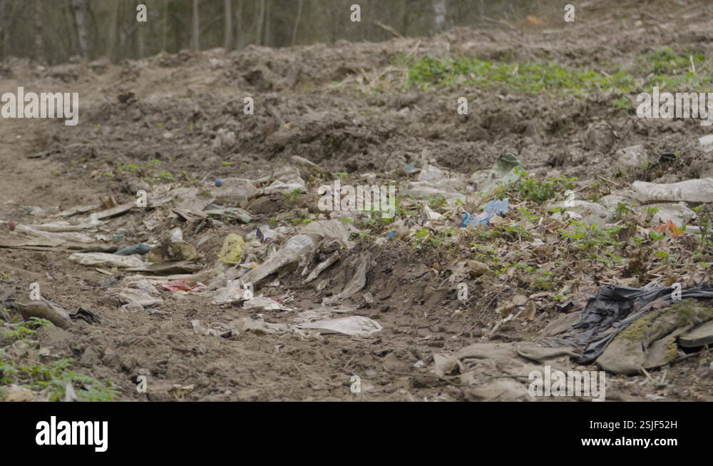 Discarded plastic waste products buried among muddy heavy duty tyre ...