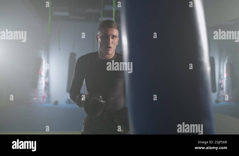 Aggressive fighter trains his punches and defense in the boxing gym, a ...