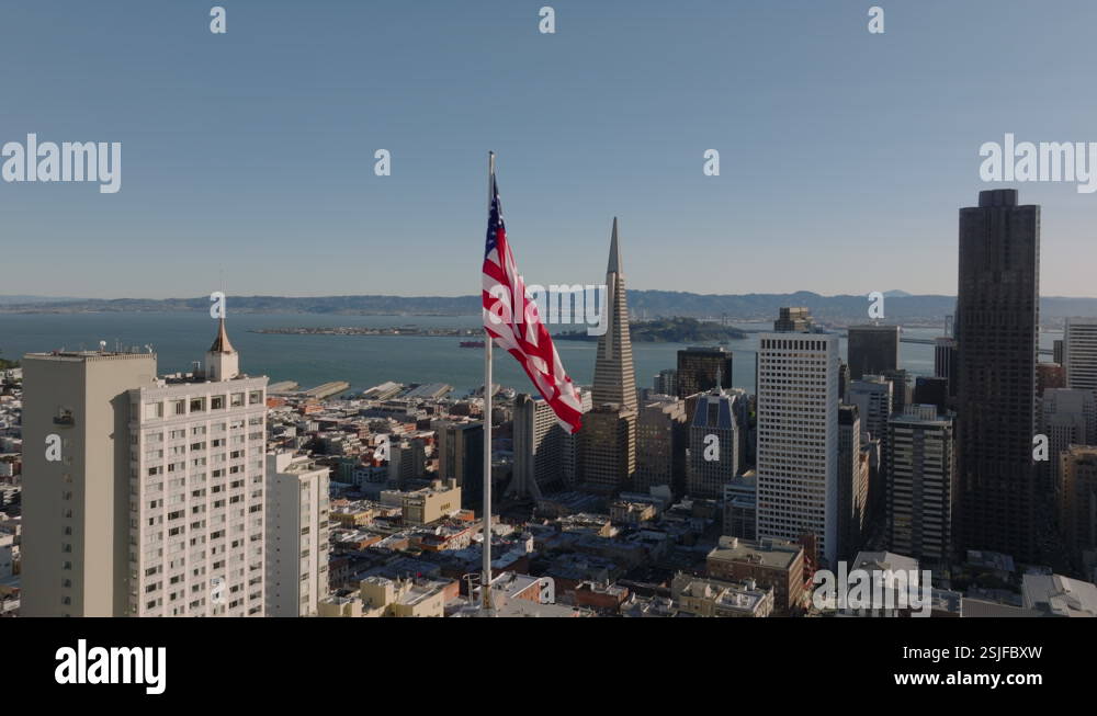Fly around US flag in height over city. Famous Transamerica Pyramid and ...