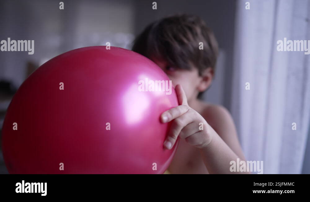 One fun child blowing up balloon with mouth. Happy small boy biting ...