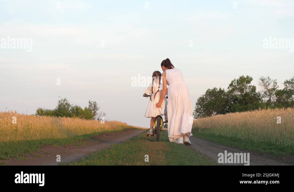 Mother teaches child girl daughter ride two-wheeled bicycle. happy ...