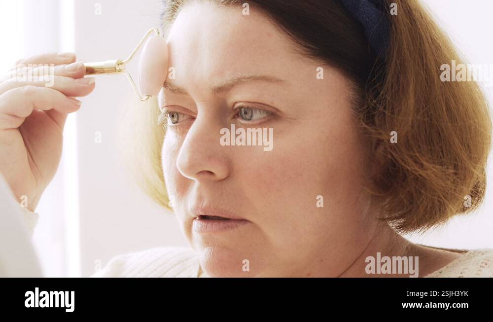 Cosmetic and skin care procedures at home. A middle aged woman massages ...