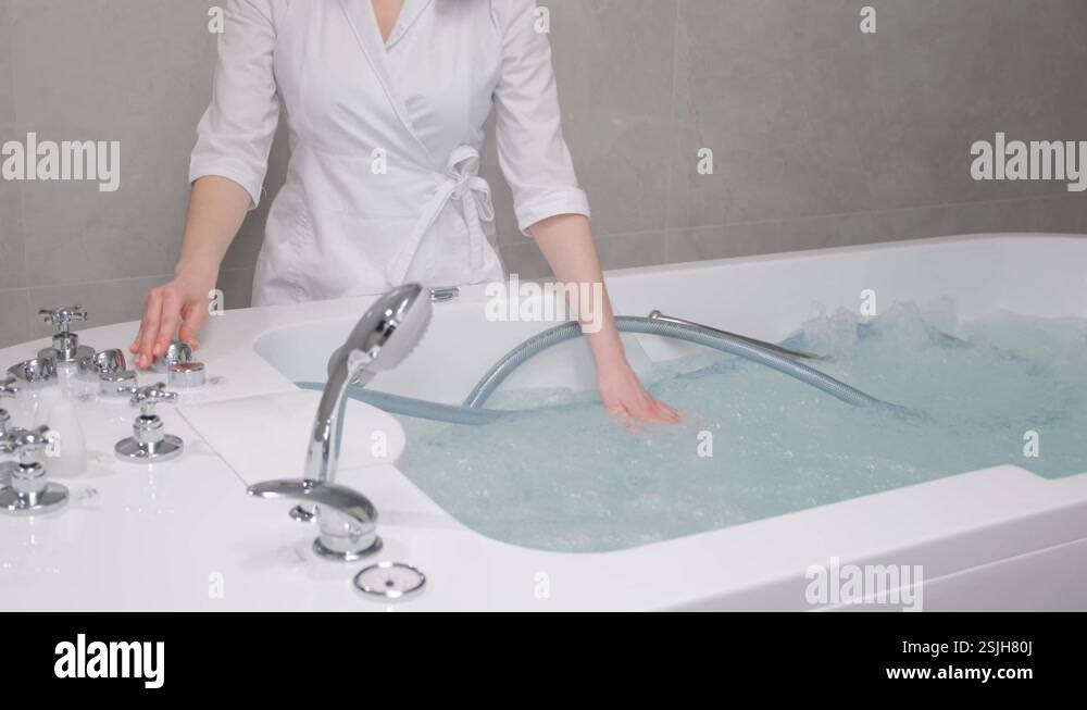 A female doctor fills a hot tub with water in a luxury spa. Relaxing ...