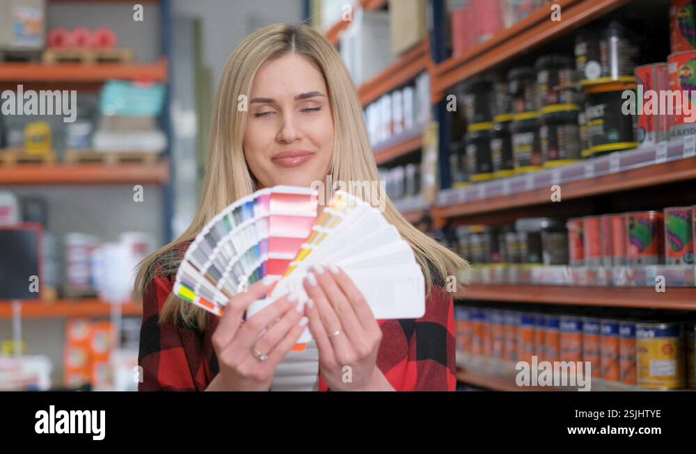 A young blonde chooses paints and brushes in a hardware store. Paint ...
