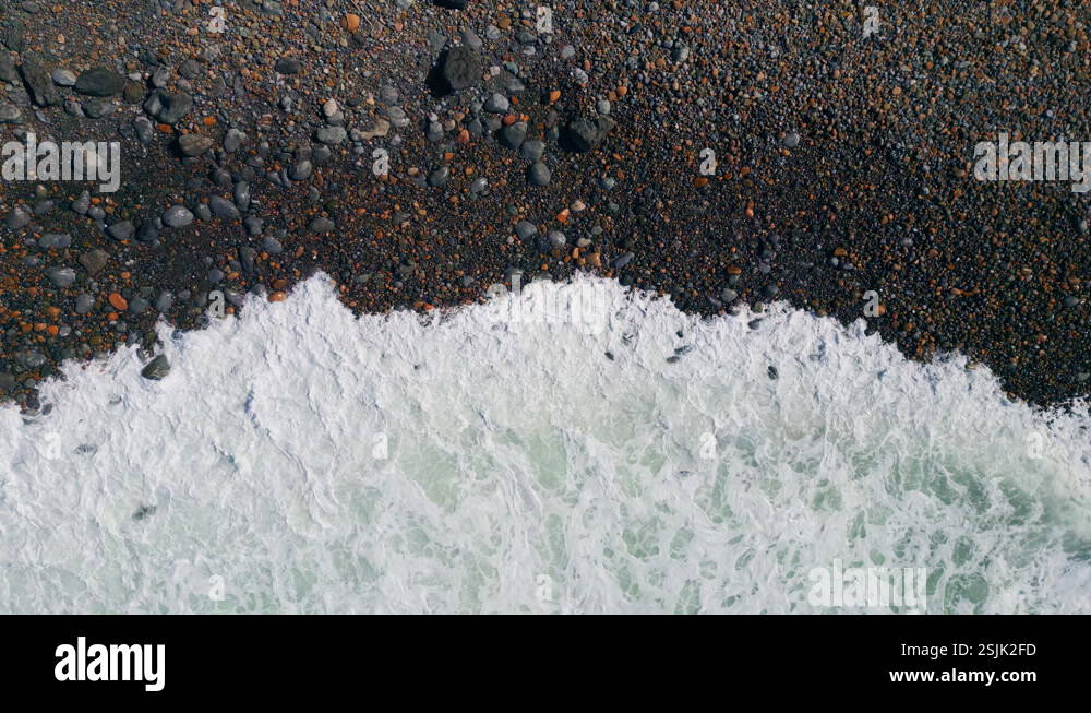 Foamy sea water washing volcanic beach stones aerial view. Ocean foam ...