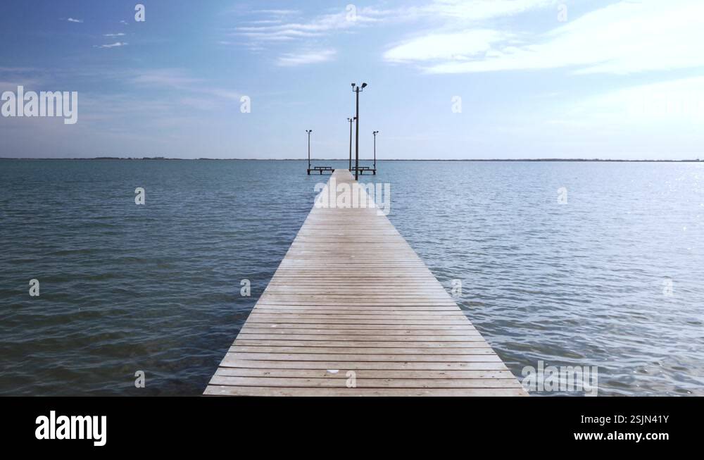 Long pier leading to the bay with street lights on a over cast day Stock Video Footage - Alamy