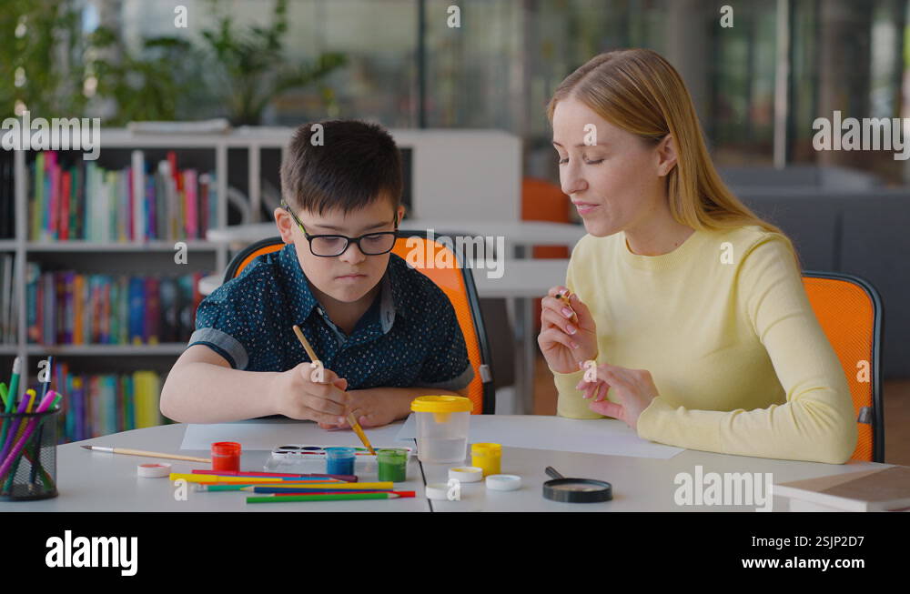 Adorable boy with Down syndrome having art class with his teacher ...