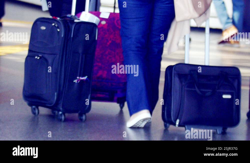 Traveler's legs walking in an airport, rolling luggage to board plane ...