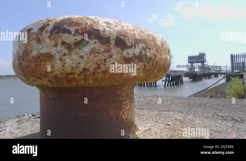 Rusted iron dock mooring with focus pull onto abandoned dock structures ...