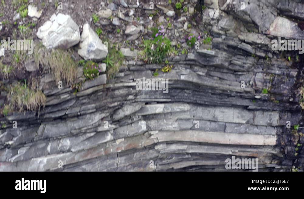 Layers of rock and sediment along exposed eroded hillslope mountain ...