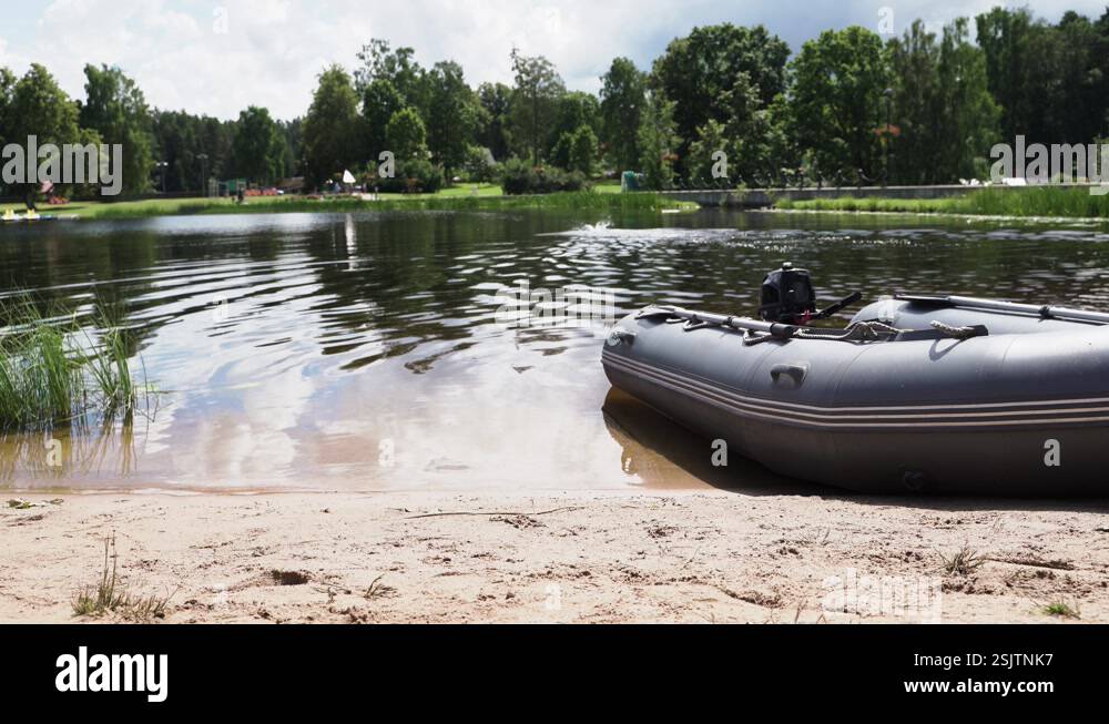 Grey inflatable lifeguard safety boat near lake with people swimming in ...