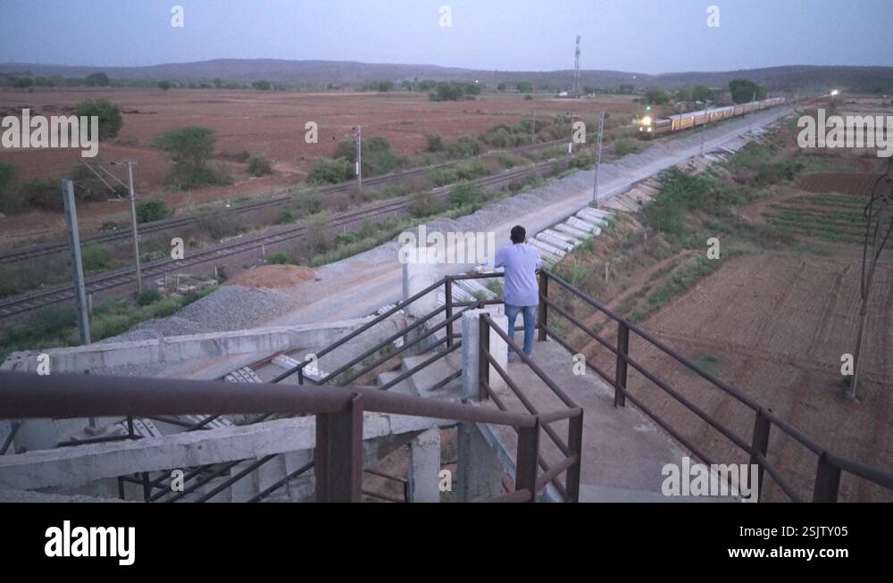 A young boy watching a train locomotive of Indian railways passing ...
