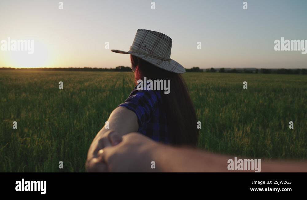 Girl, boy in love walk across field, holding hands. Follow me young ...