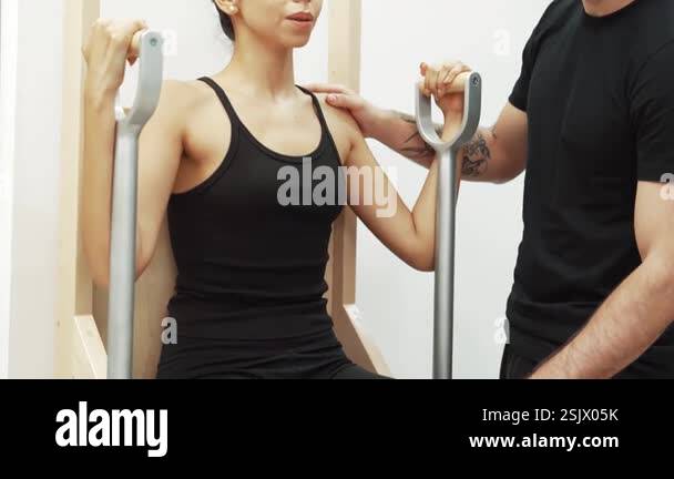 Instructor guiding student Pilates leg press on Wunda Chair equipment ...