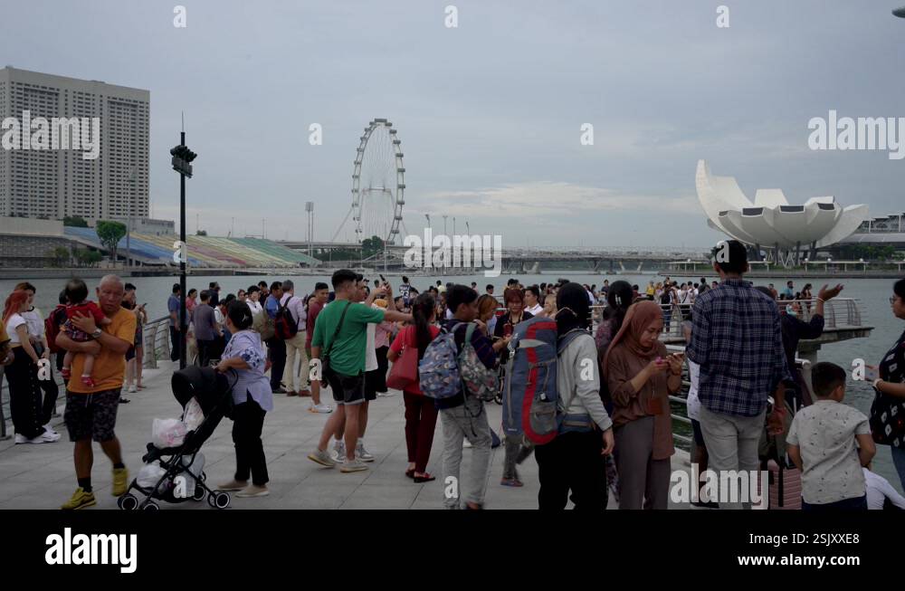 Crowd of tourists pose and take photos of the Merlion statue at Merlion ...