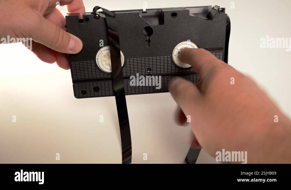 Manually rewinding the VHS tape onto the reel inside the cassette Stock ...