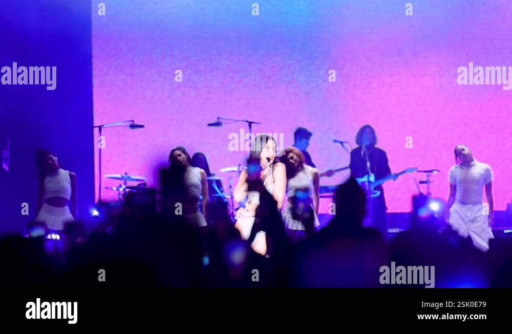 Dua Lipa performing live on stage with dancers and band in background ...