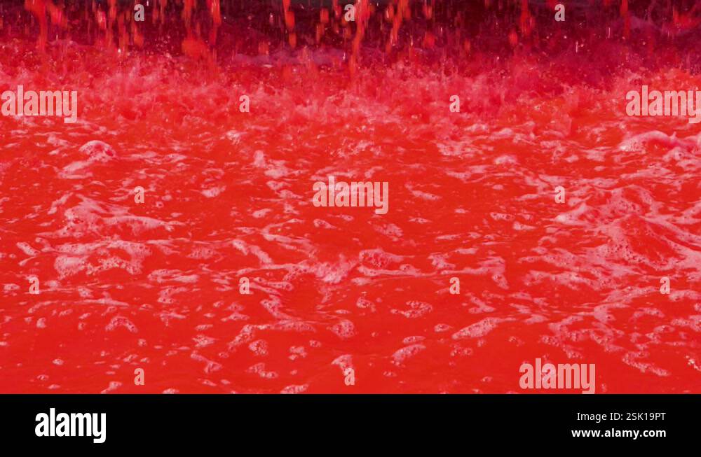 Bloody red color water splashing in slow motion on a rippled surface ...