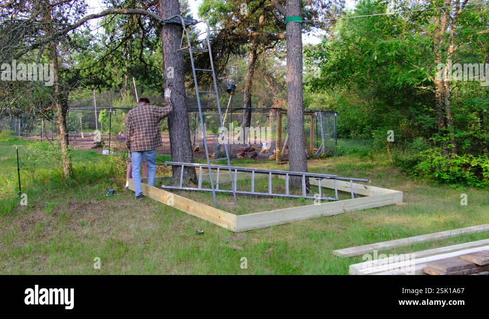 Men drilling hole in ground for post mounting for future zip line ...