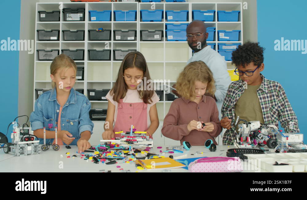 Young Kids Making Robots at Hobby Club, and Male Teacher Checking Stock ...