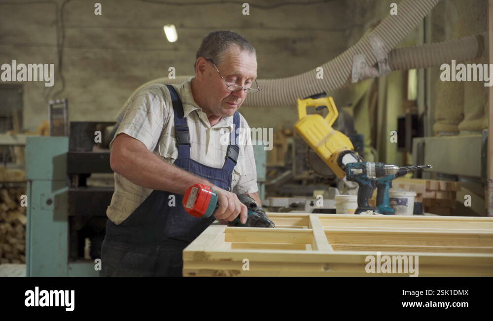 Worker using the wood drilling tool to drill holes inside window frame ...