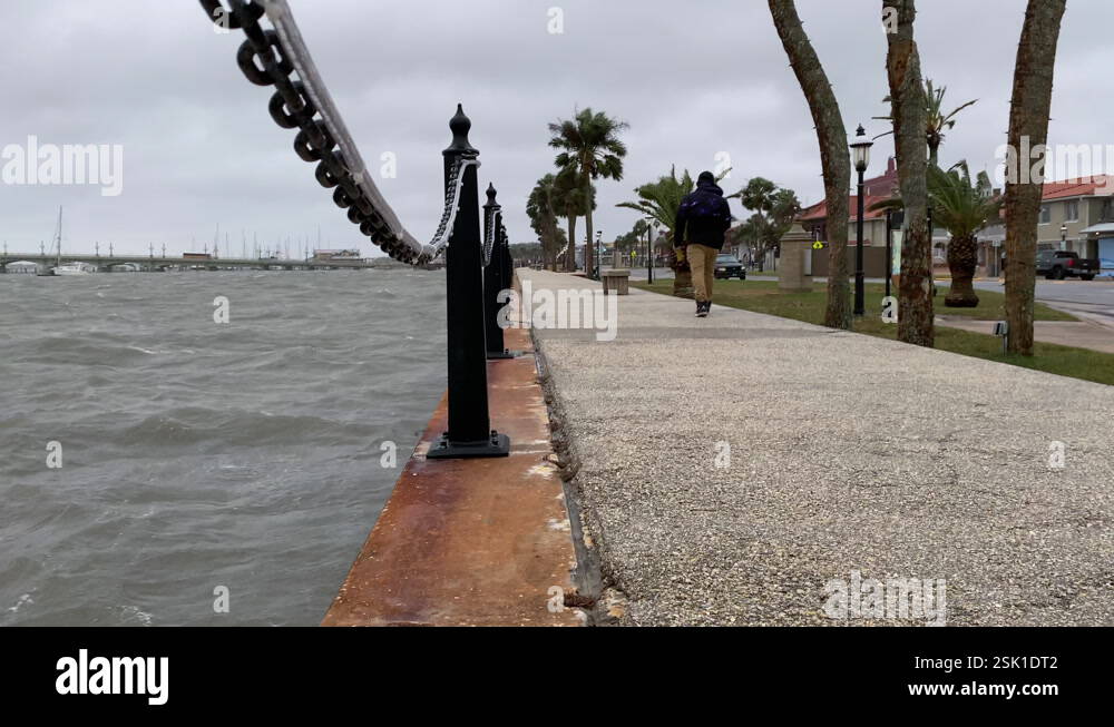 Man walking on ocean bulkhead in wind as damaging hurricane waves surge ...