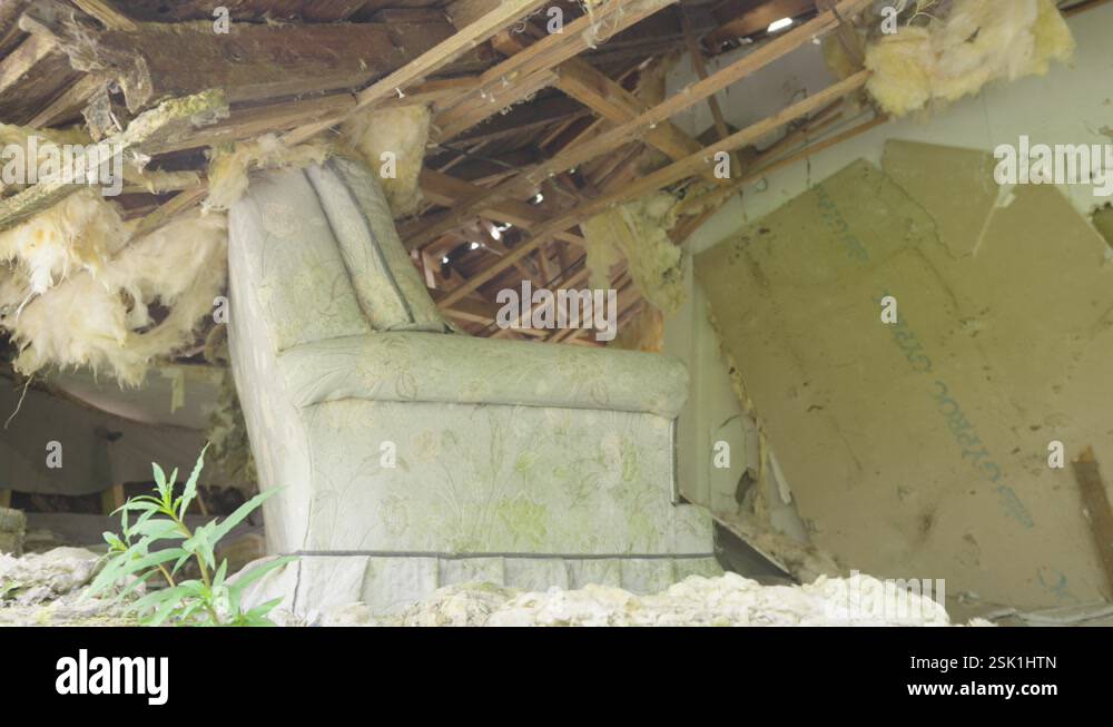 The roof of a destroyed building is held up by an armchair, locked off ...