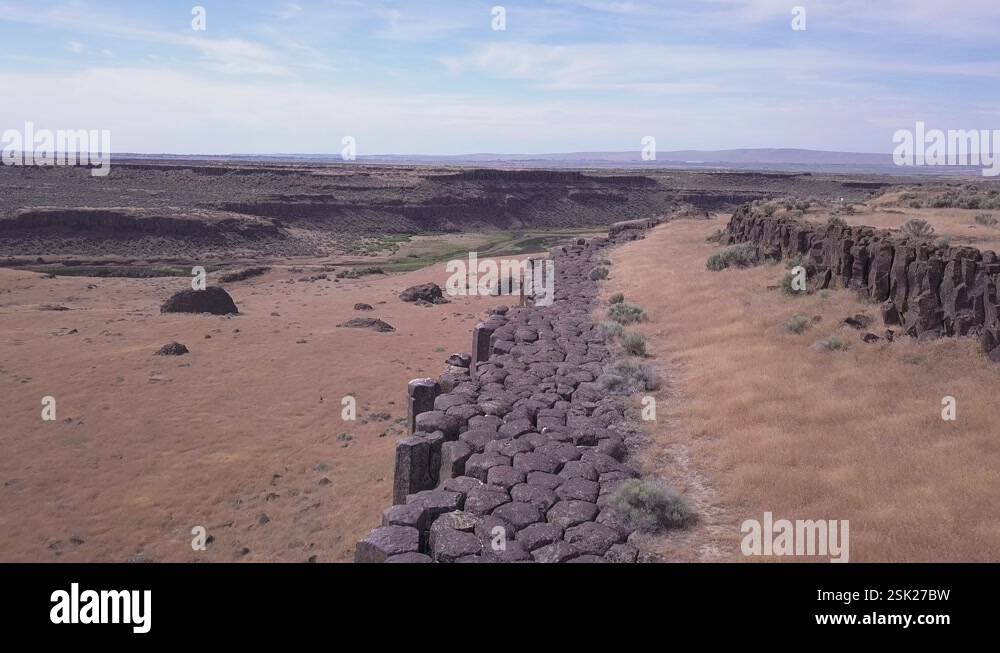 Aerial flight along top of arid basalt column cliff in Scablands, WA ...