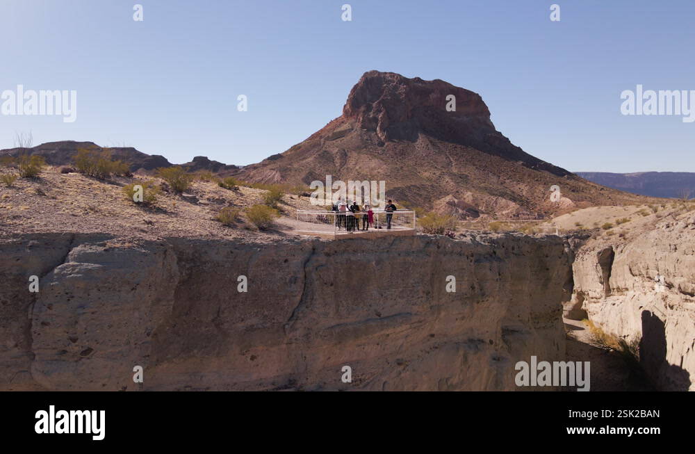 Group of travelers stand at fenced lookout point above sandstone cliffs ...