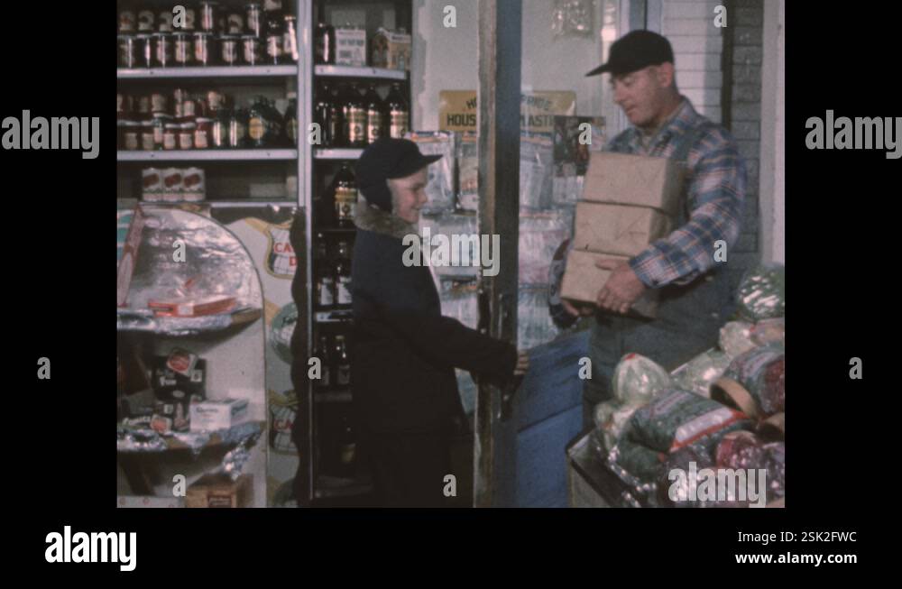 1950s: Boy and man enter a grocery store. Man carries in boxes. Girls ...