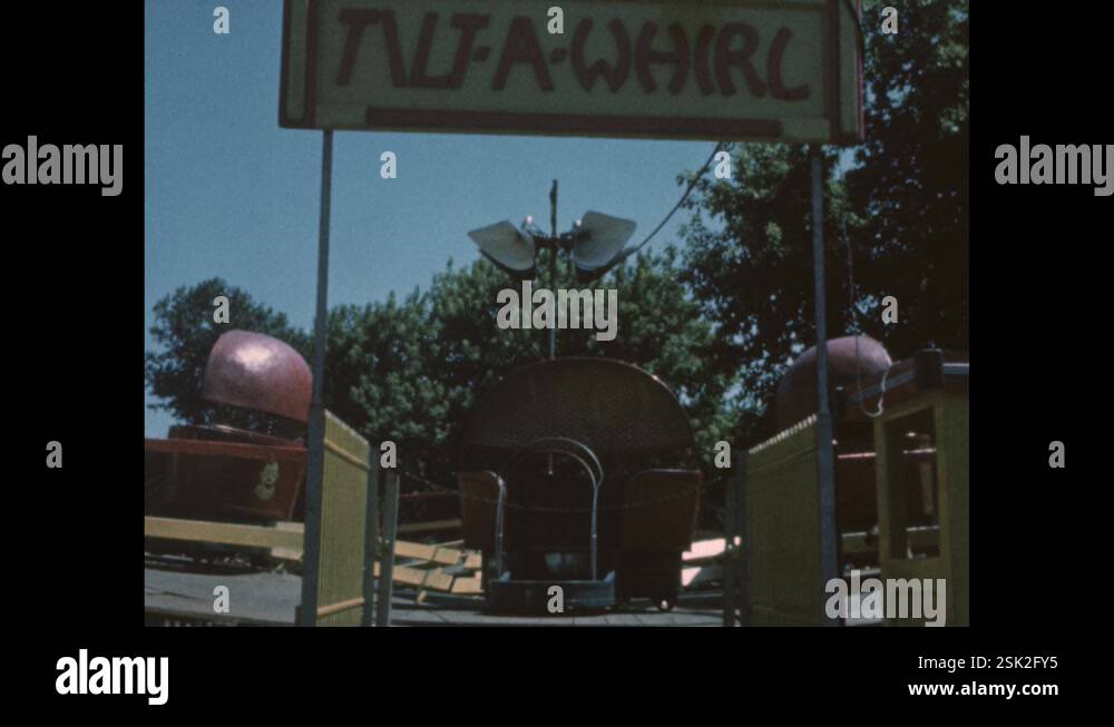 1950s: Idle Tilt-A-Whirl ride. Boy plays with a dog on the lawn in ...